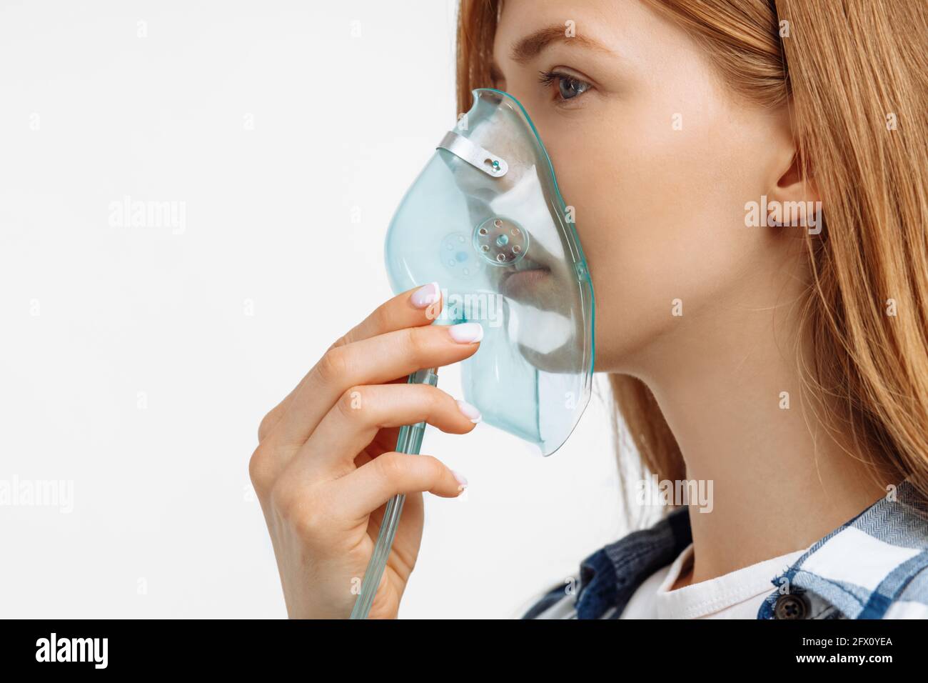 Young woman holding inhalation mask in front of her face, on white ...