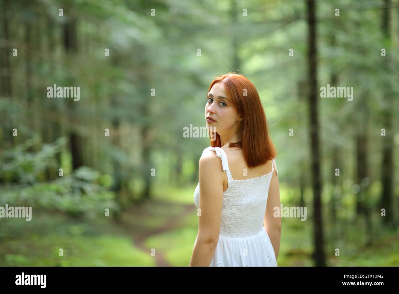 Beautiful Woman Walking Alone In A Green Forest Looking At Camera In