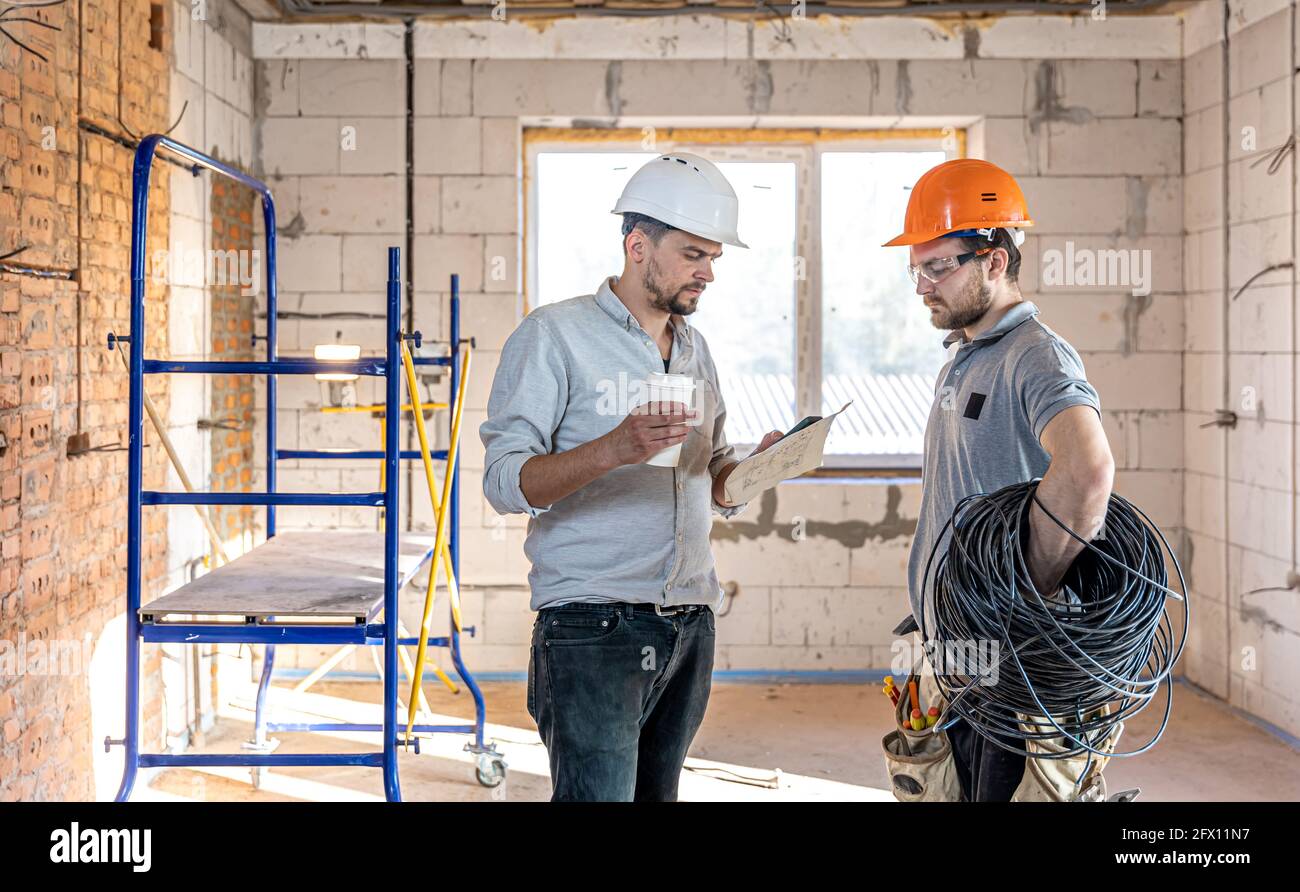 Two builder engineers talking at a building site, engineer explaining a ...