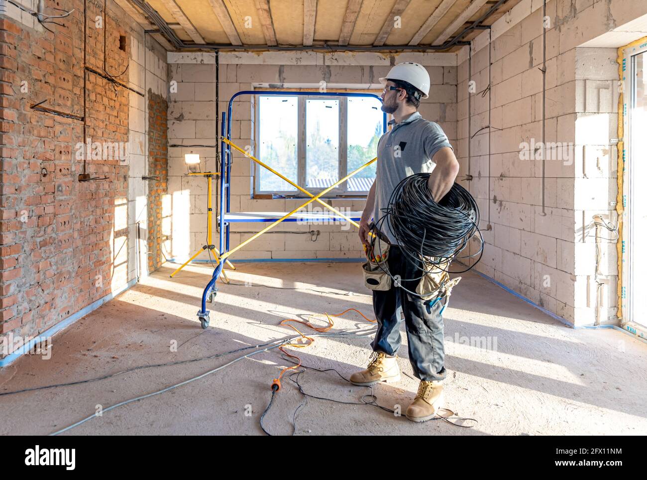 An electrician examines a construction drawing while holding an ...