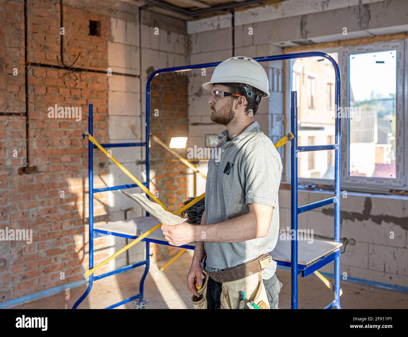 An electrician examines a construction drawing at a work site Stock ...