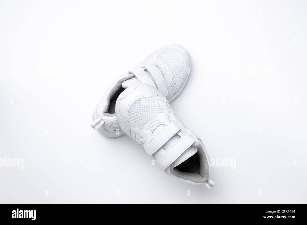 top view on a pyramid of white child sneakers, one sneaker lies on ...