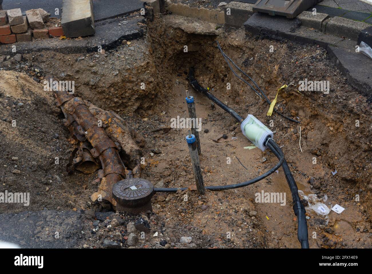 Dug up sidewalk revealing wires in protective tubes. Building of ...