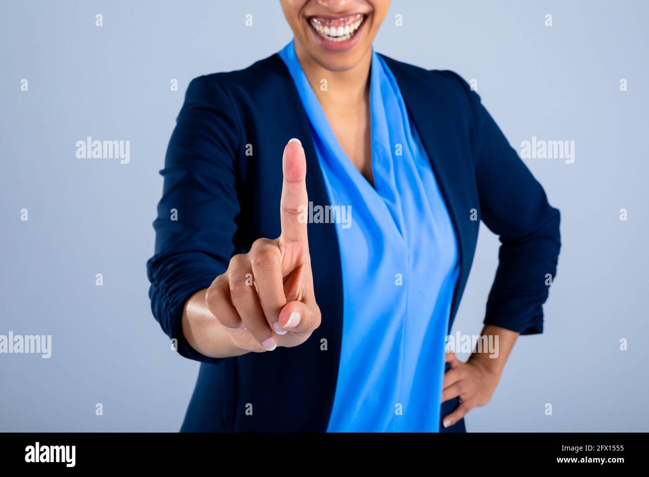 Mid section of businesswoman smiling while touching invisible screen ...
