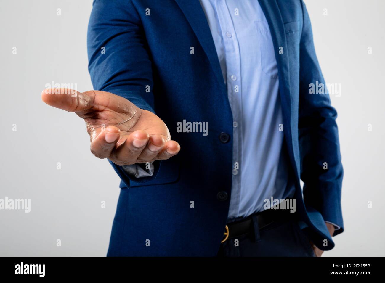 Mid section of businessman holding a invisible object against grey ...