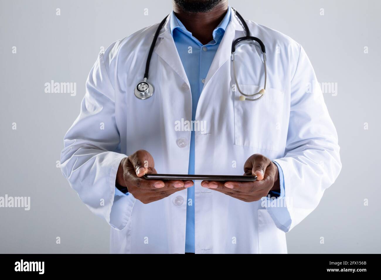 Mid section of african american male doctor holding digital tablet ...