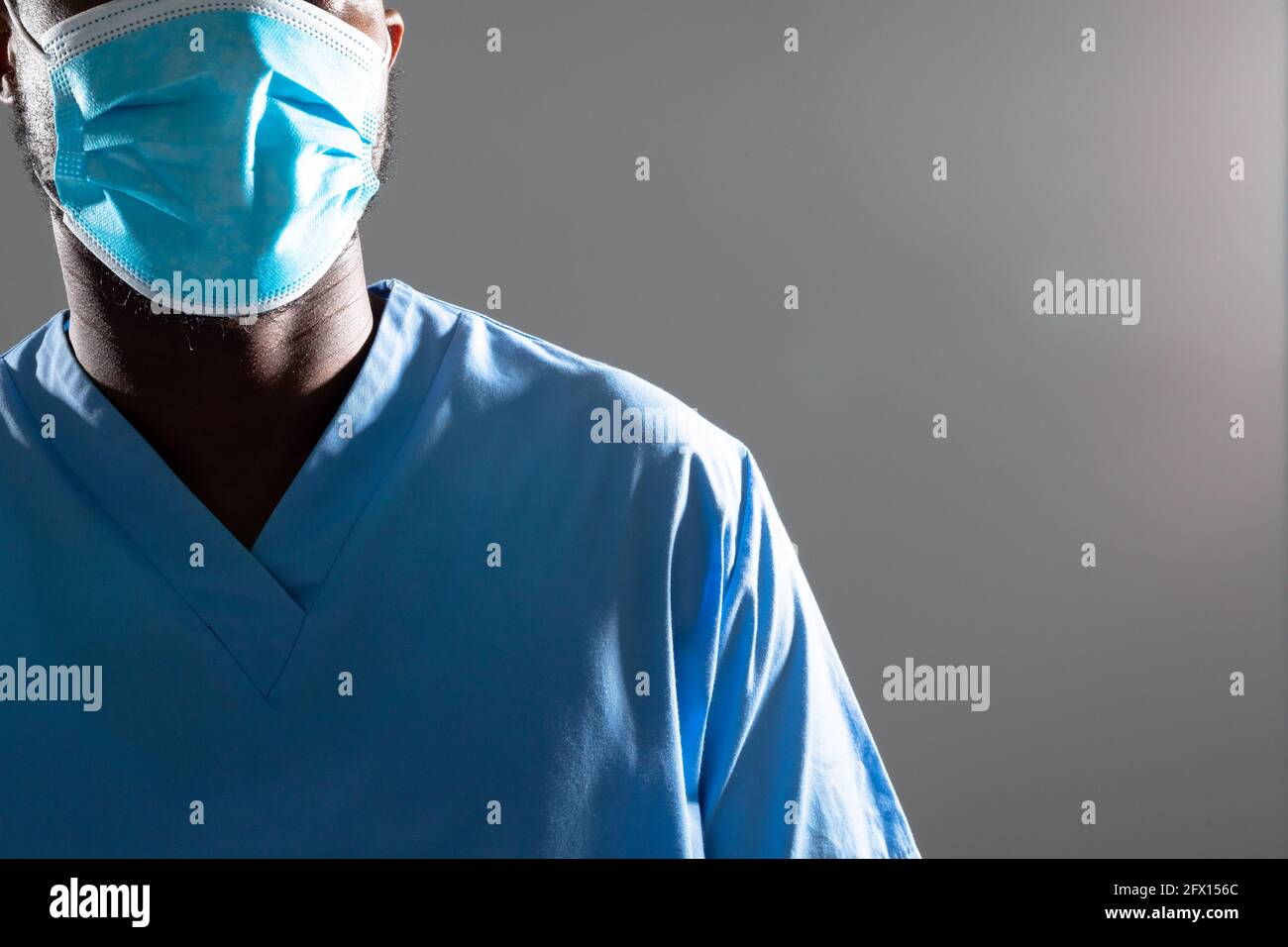 Mid section of african american male health worker wearing face mask ...