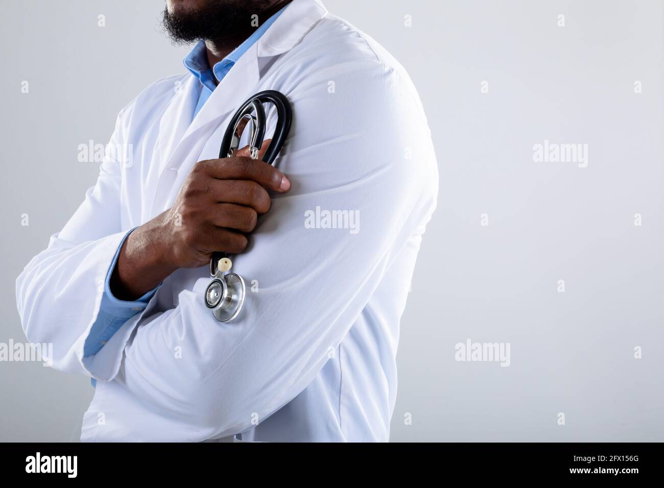 Mid section of african american male doctor holding stethoscope against ...