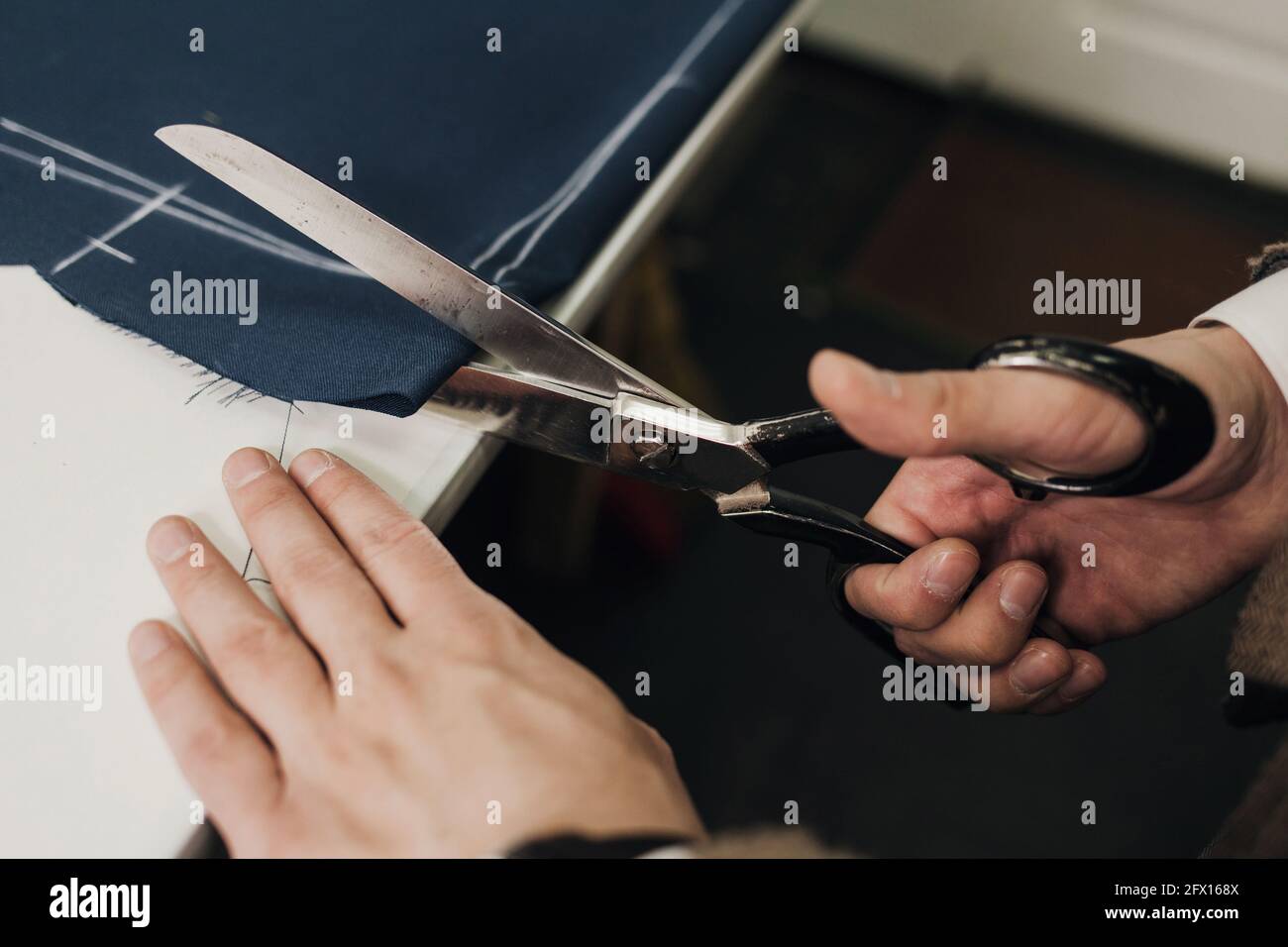 fashion designer at work. the tailor cuts the fabric with scissors ...