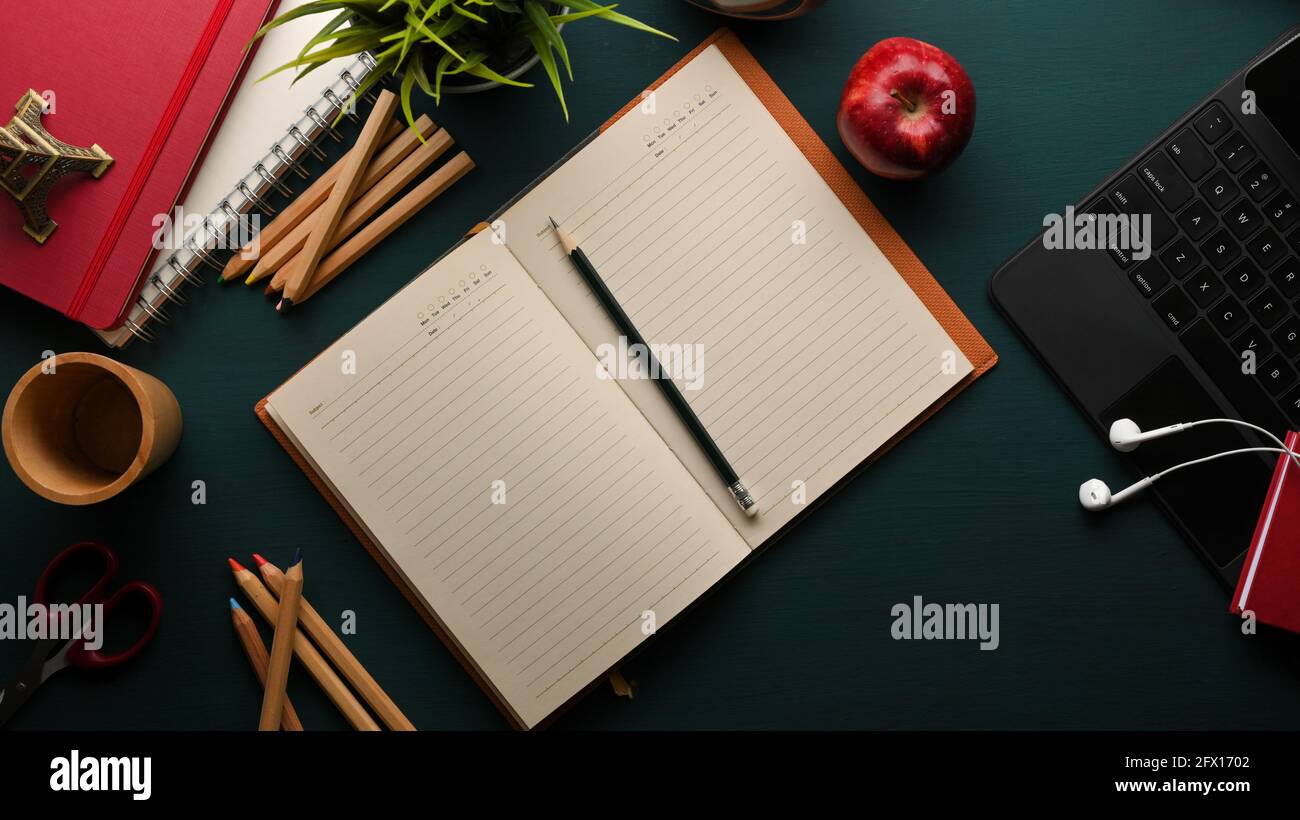 Top view of study table with opened notebook, stationery, tablet and ...