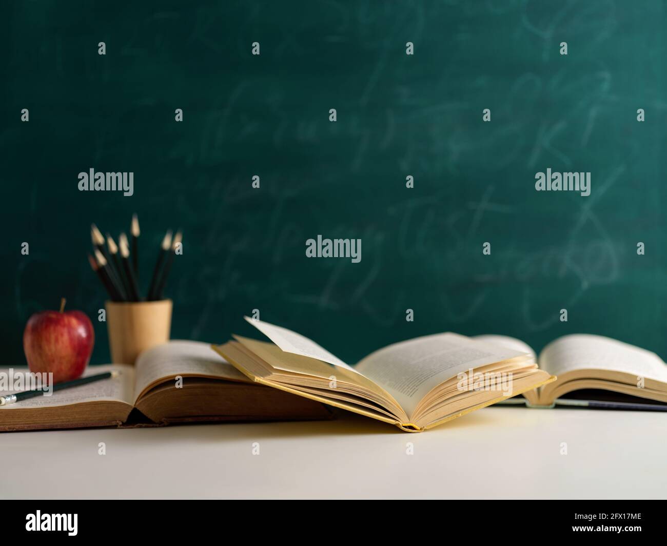 Close up view of study table with opened books, pencils and apple on ...