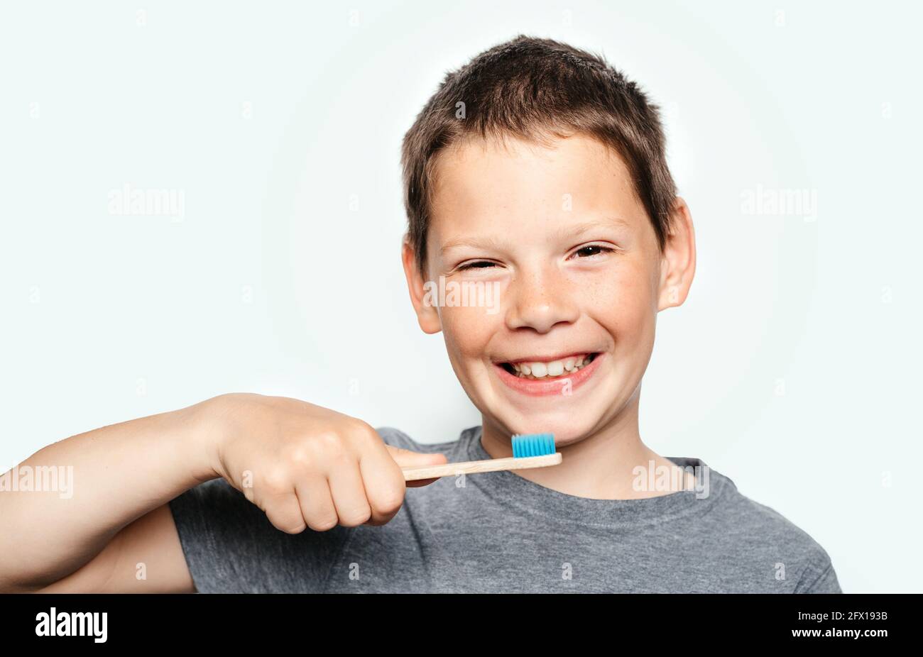 A smiling boy holding bamboo eco-friendly tooth brush and showing his ...