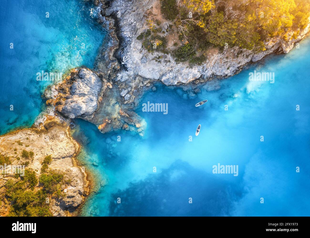 Aerial view of floating board and people on blue sea, rocks Stock Photo ...
