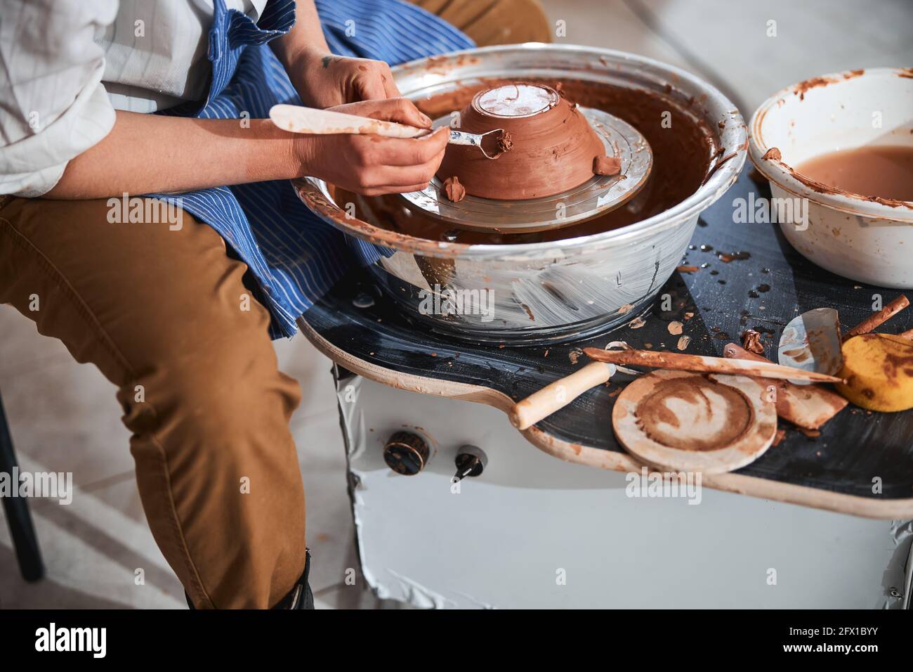 Craftsman using pottery loop tool while trimming clay dish Stock Photo ...