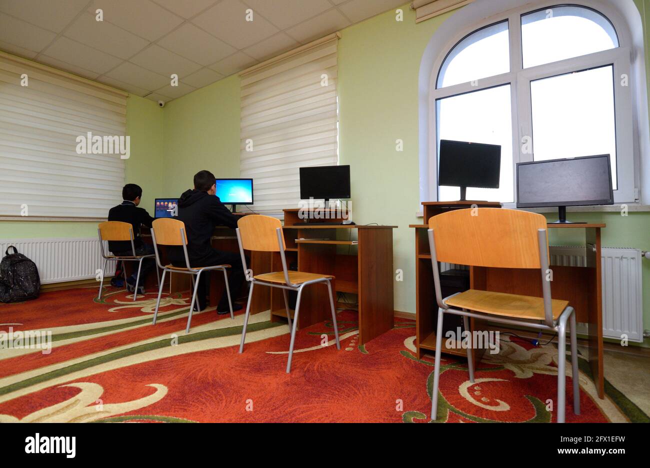 Computer room. Two boys sitting at desks in front of monitors of ...