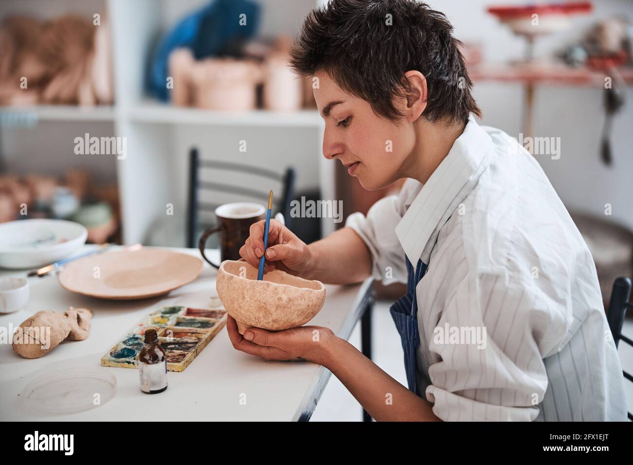 Peaceful pottery designer working on painting in clay bowl Stock Photo ...