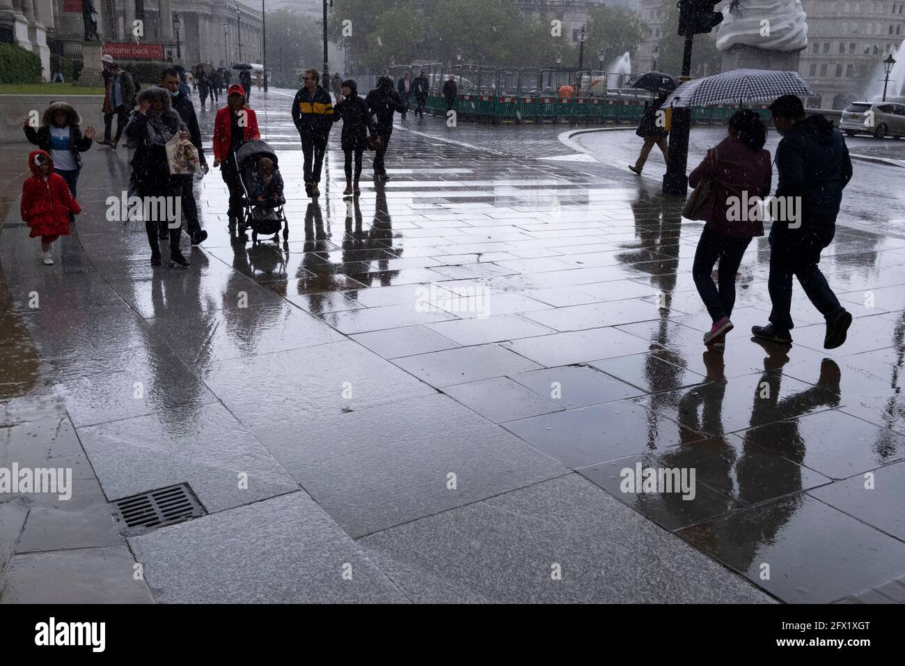 Wet Londoners walk along the paved area outside the National Gallery ...