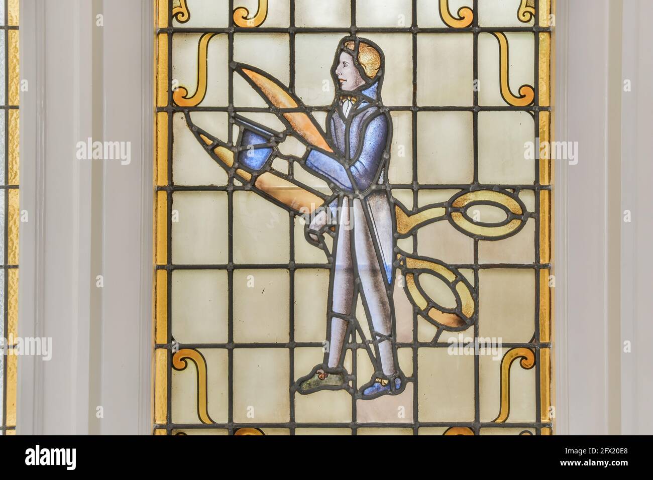 Aged stained glass window with figure of gentleman in suit and scissors ...