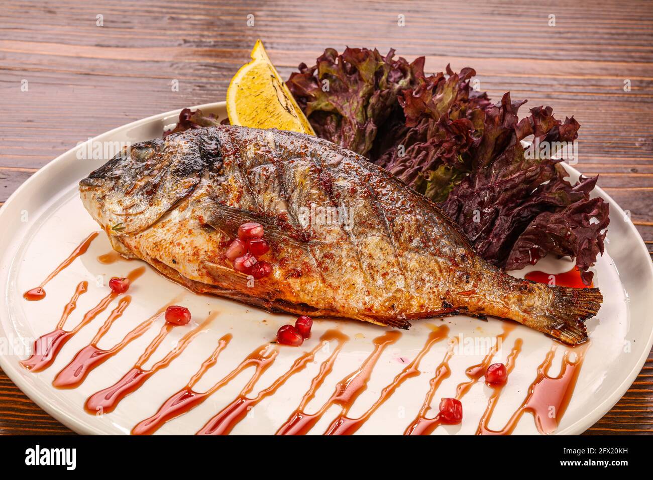 Grilled dorada fish served lemon and salad leaves Stock Photo - Alamy