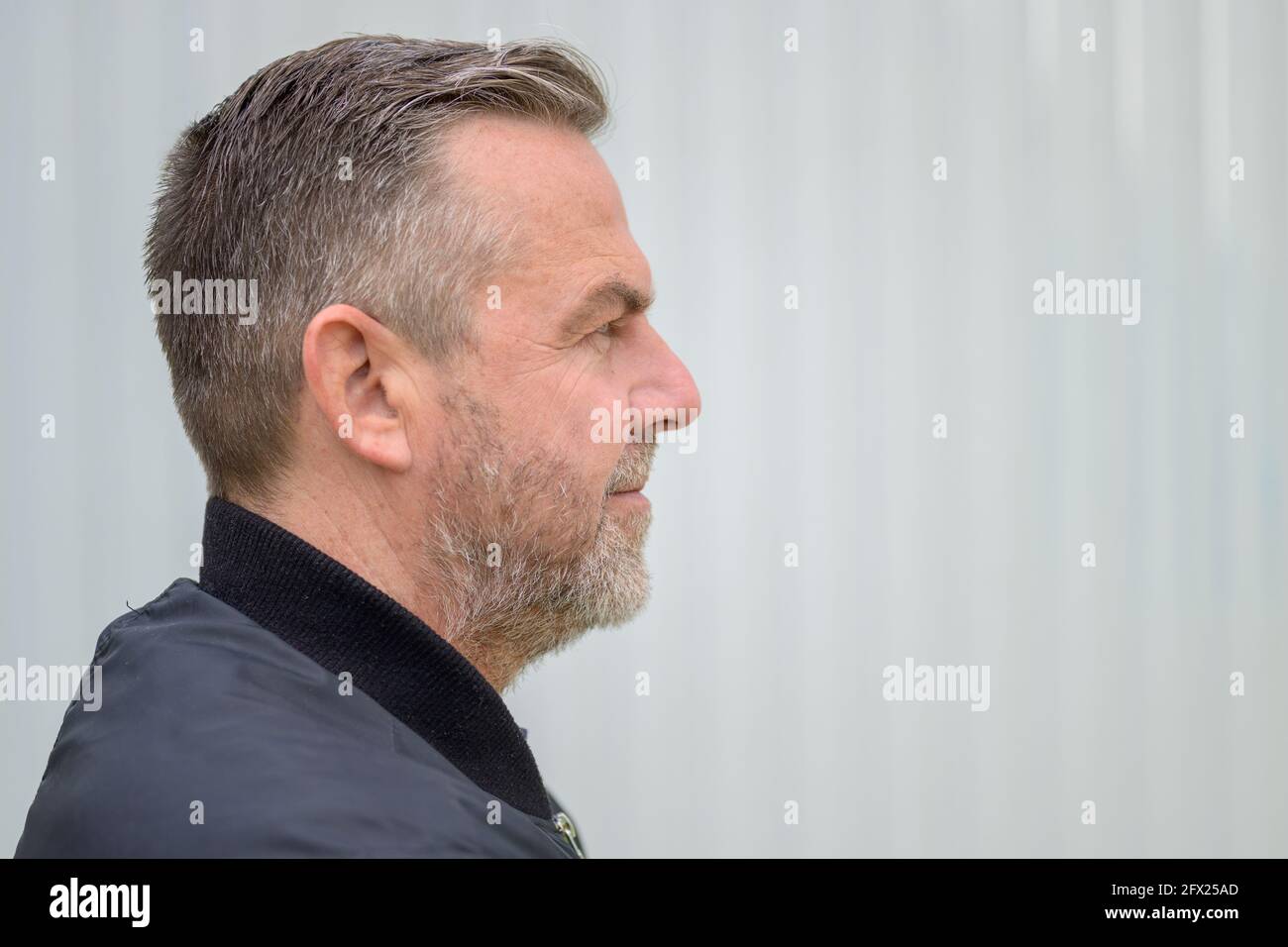 Profile view of a serious middle-aged man with beard looking towards ...