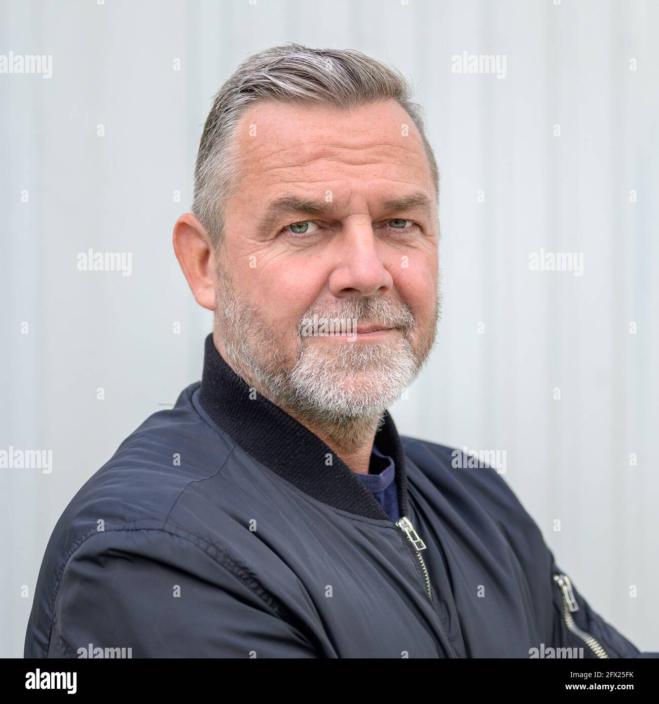 Serious middle-aged man with grey hair looking pensively at the camera ...