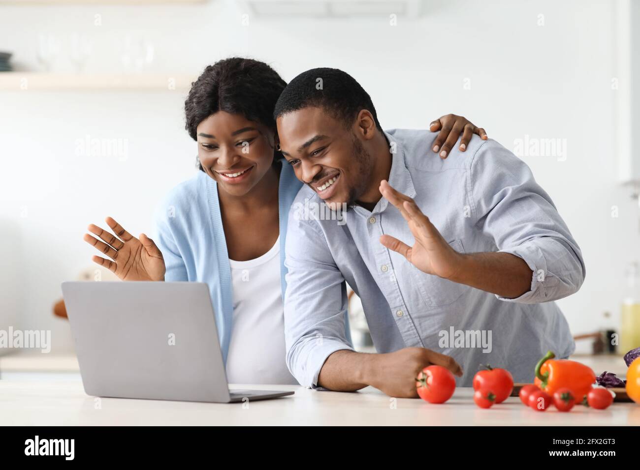 Cheerful pregnant black couple having video call while cooking Stock ...