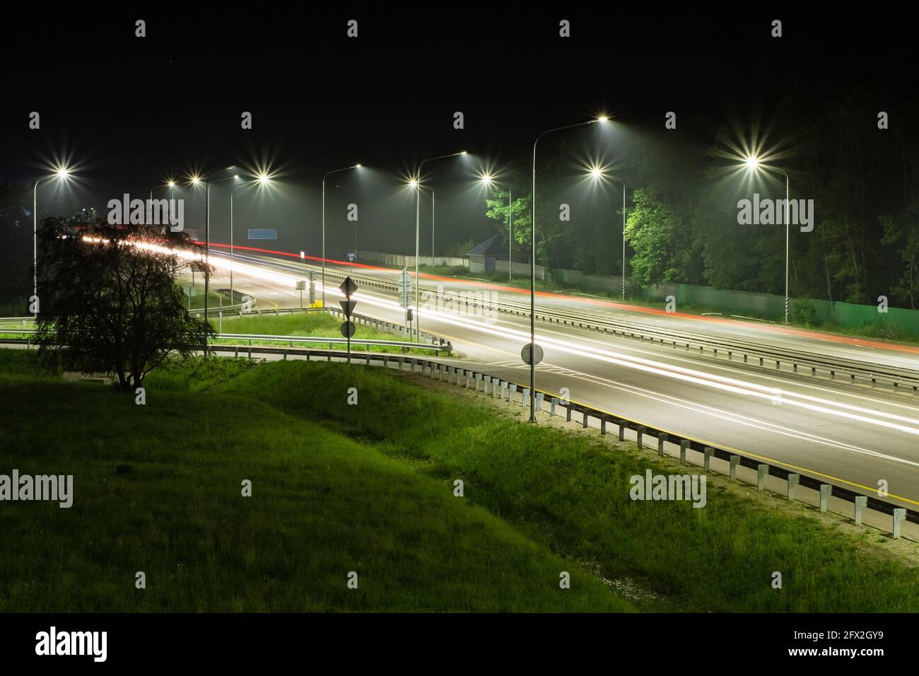 Night highway in the light of streetlights and the plumes of headlights ...