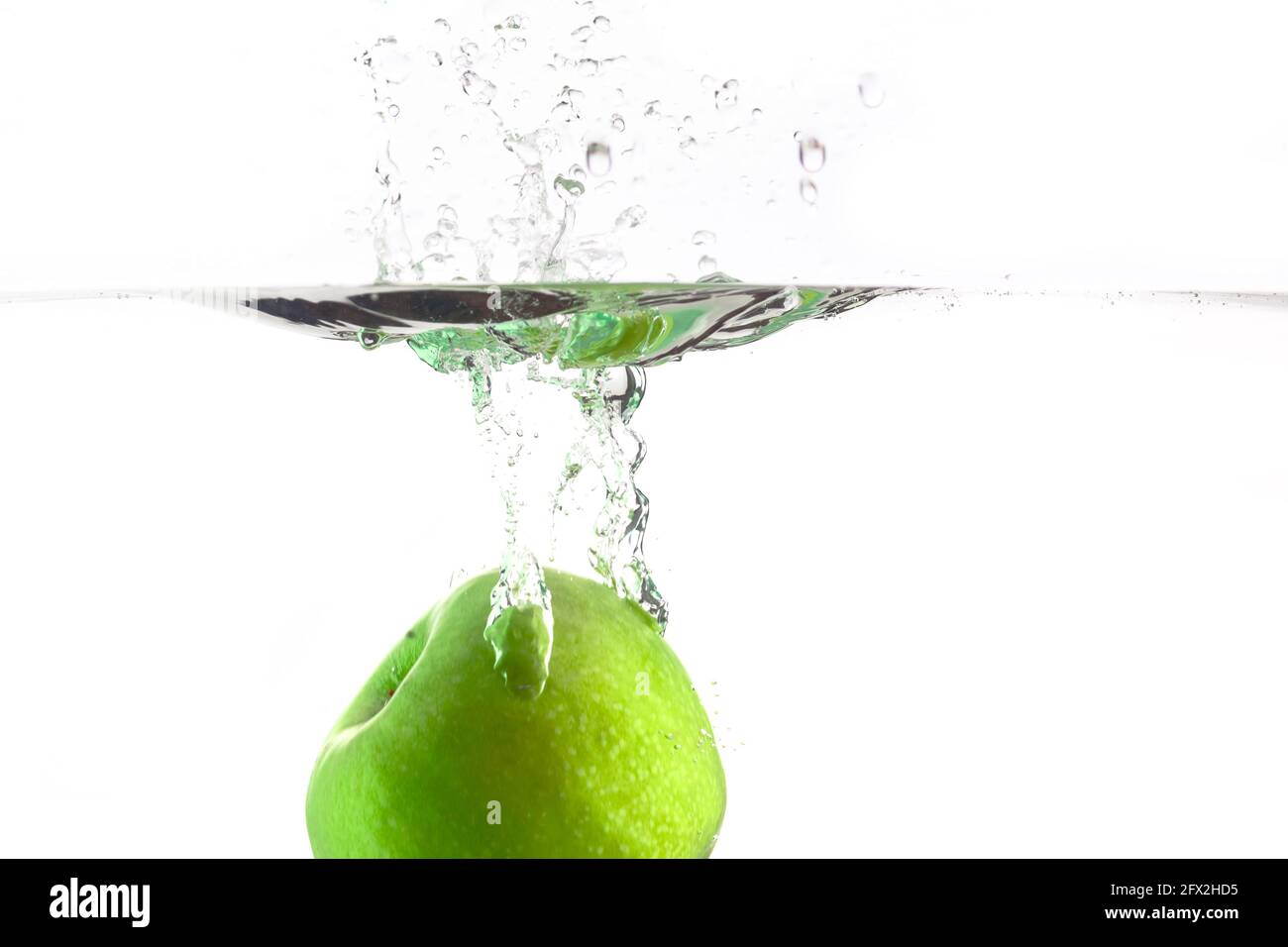 drop one green apple into the water with splashes on a white background ...