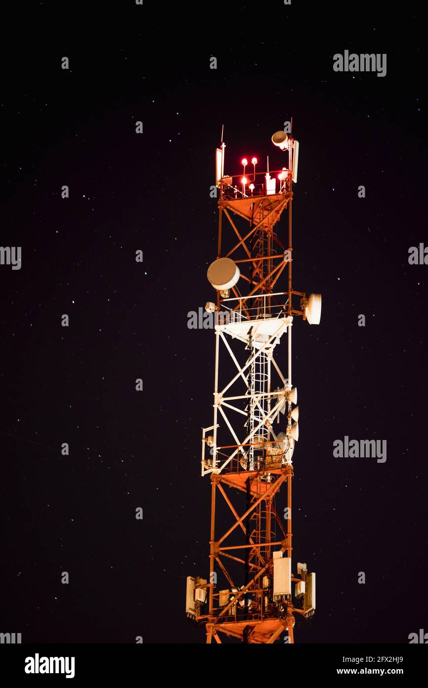 Red and white cell tower on the background of the starry sky. Mobile ...
