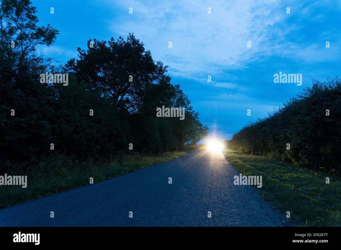 A long straight road, With car headlights in the distance. On a summers ...