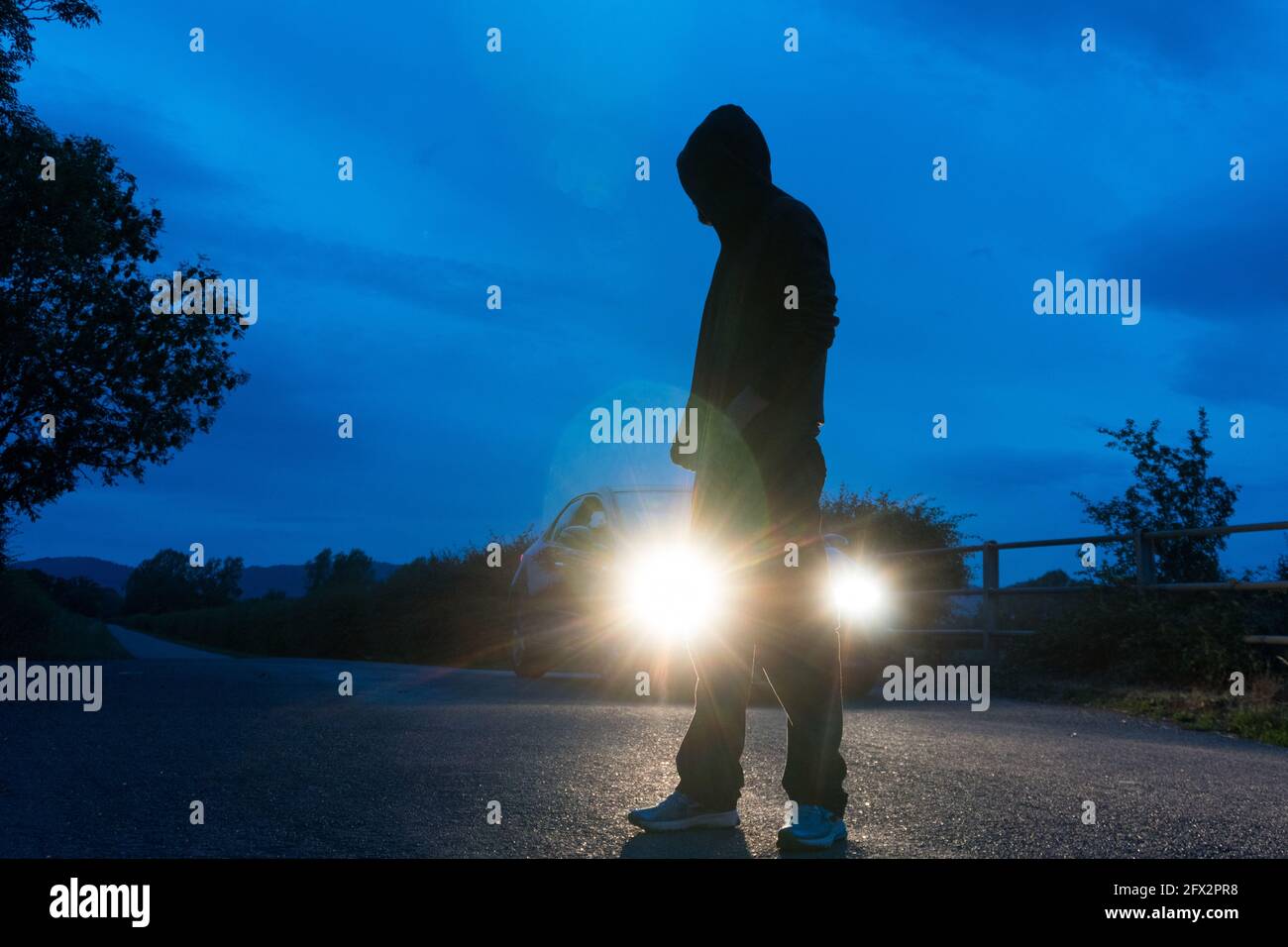 A mysterious hooded man, back to camera. looking at a long straight ...