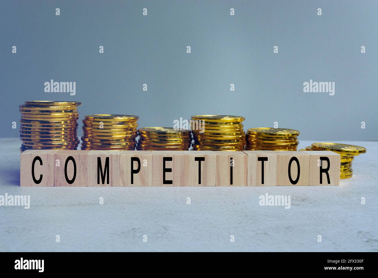 Competitor text on wood block with a pile of gold coins Stock Photo - Alamy