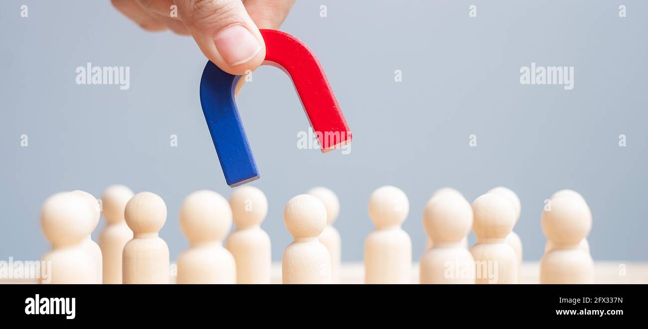 Business man hand holding magnet and pulling man wooden figure from the ...