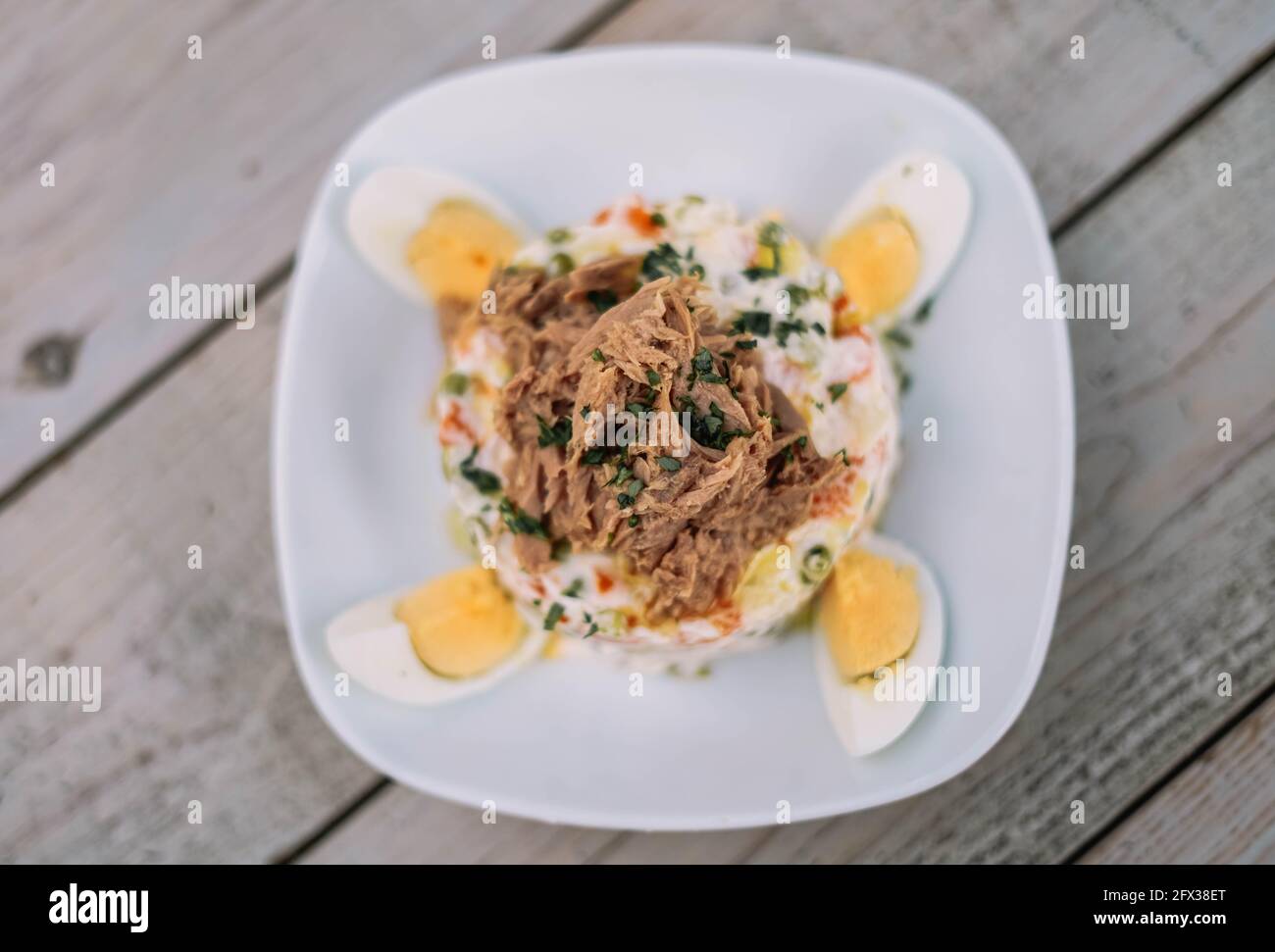 Russian salad with tuna, potatoes, hard-boiled egg, peas, carrot and ...