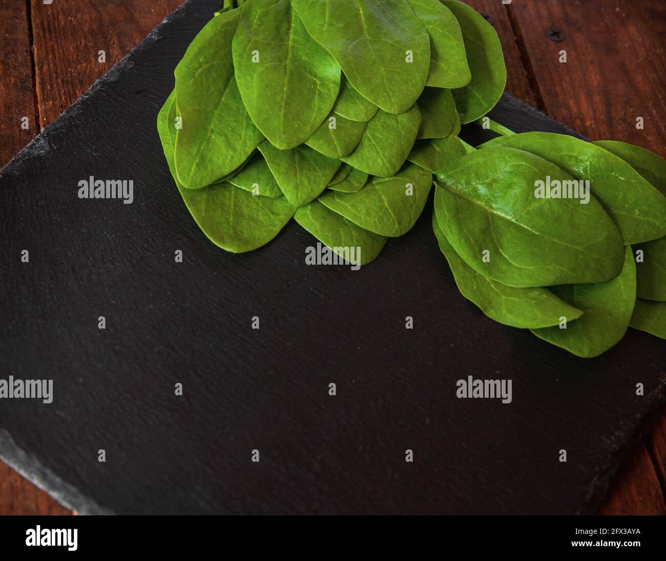 bright green fresh spinach lie on a black serving board Stock Photo - Alamy