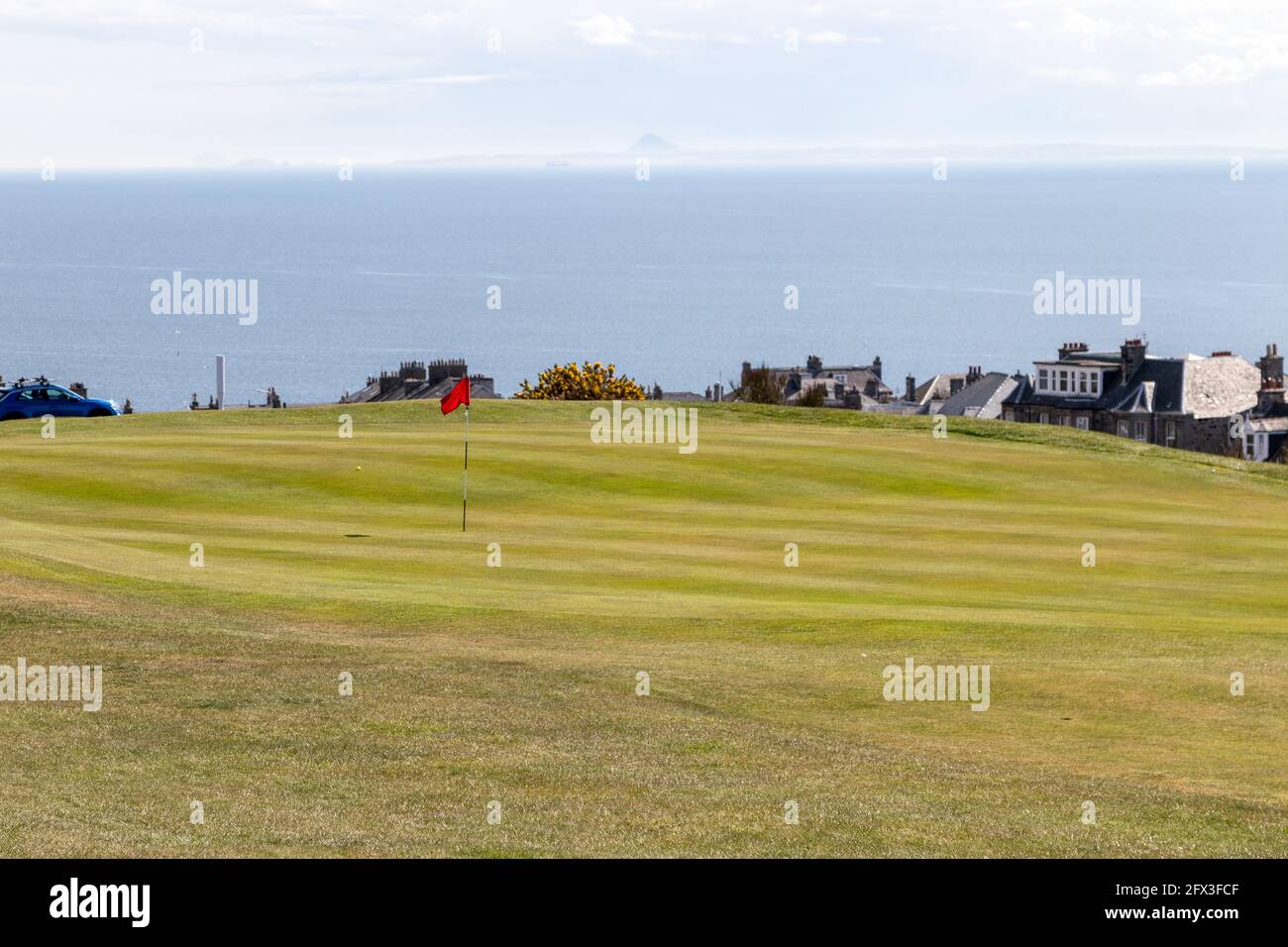 Red flag on a green at Kinghorn Golf Course with the sea in the ...