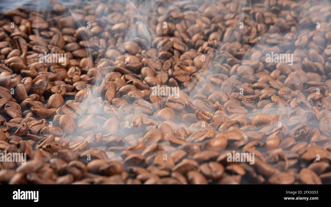 Roasted coffee on rustic sieve with smoke and with black background ...