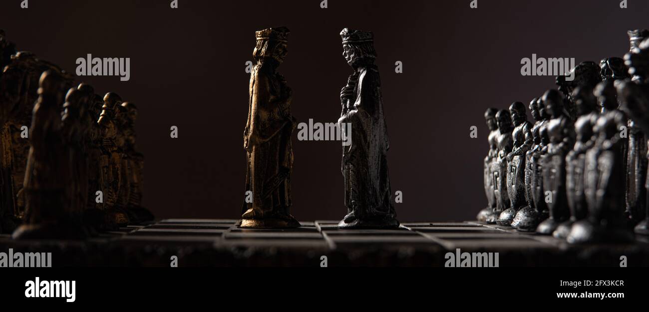 stylized chess pieces on a board with black background, selective focus ...
