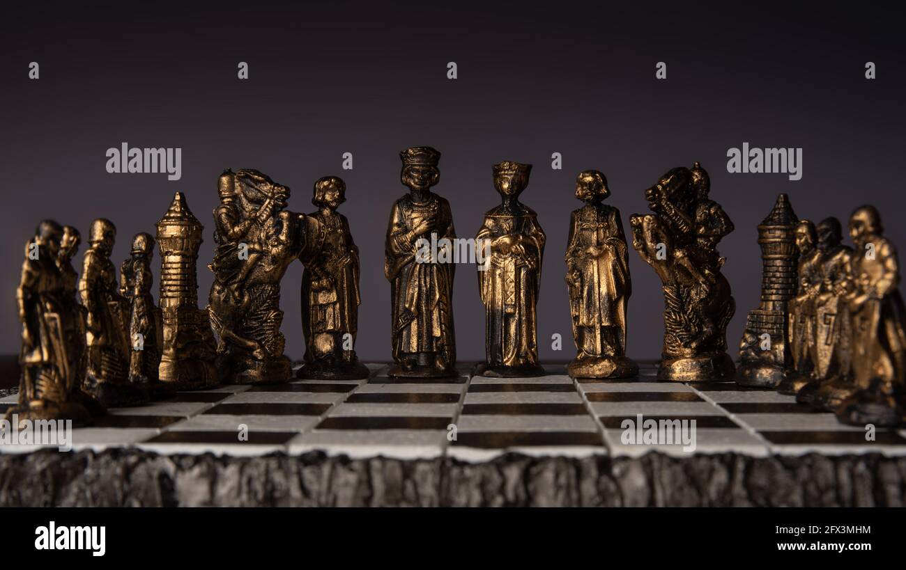 stylized chess pieces on a board with black background, selective focus ...