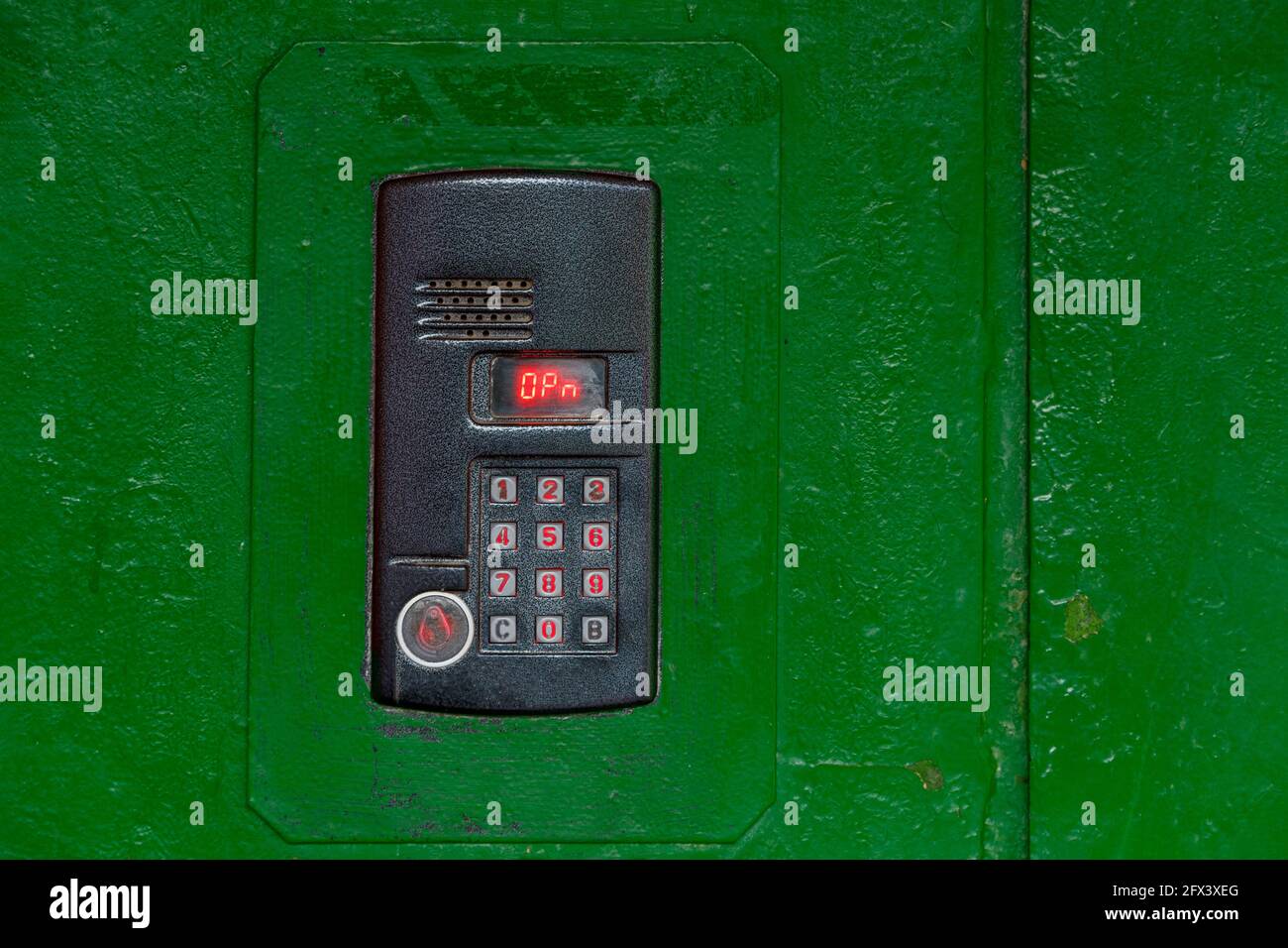 An intercom on green painted red steel surface with a keypad, digital ...