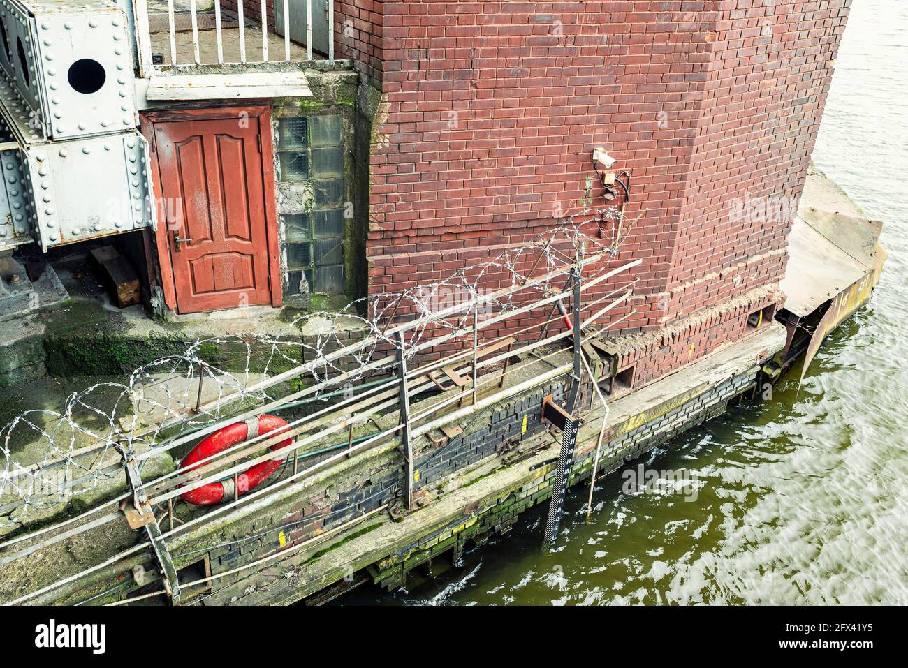 Door in old railroad brick bridge building by river, red life ring ...