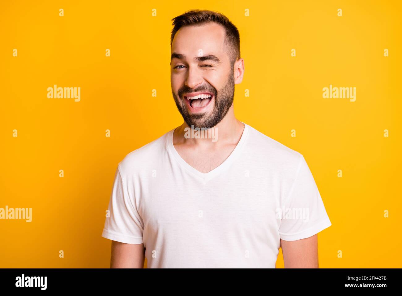 Portrait of cool guy blink wear white t-shirt isolated on vibrant ...