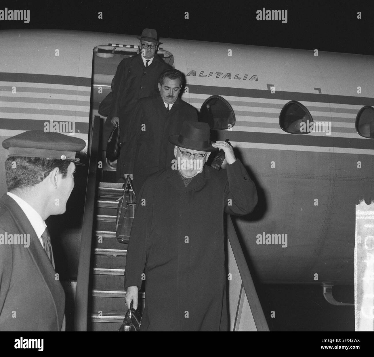 The cardinal (r.) as he descends the airplane stairs and holds his hat ...