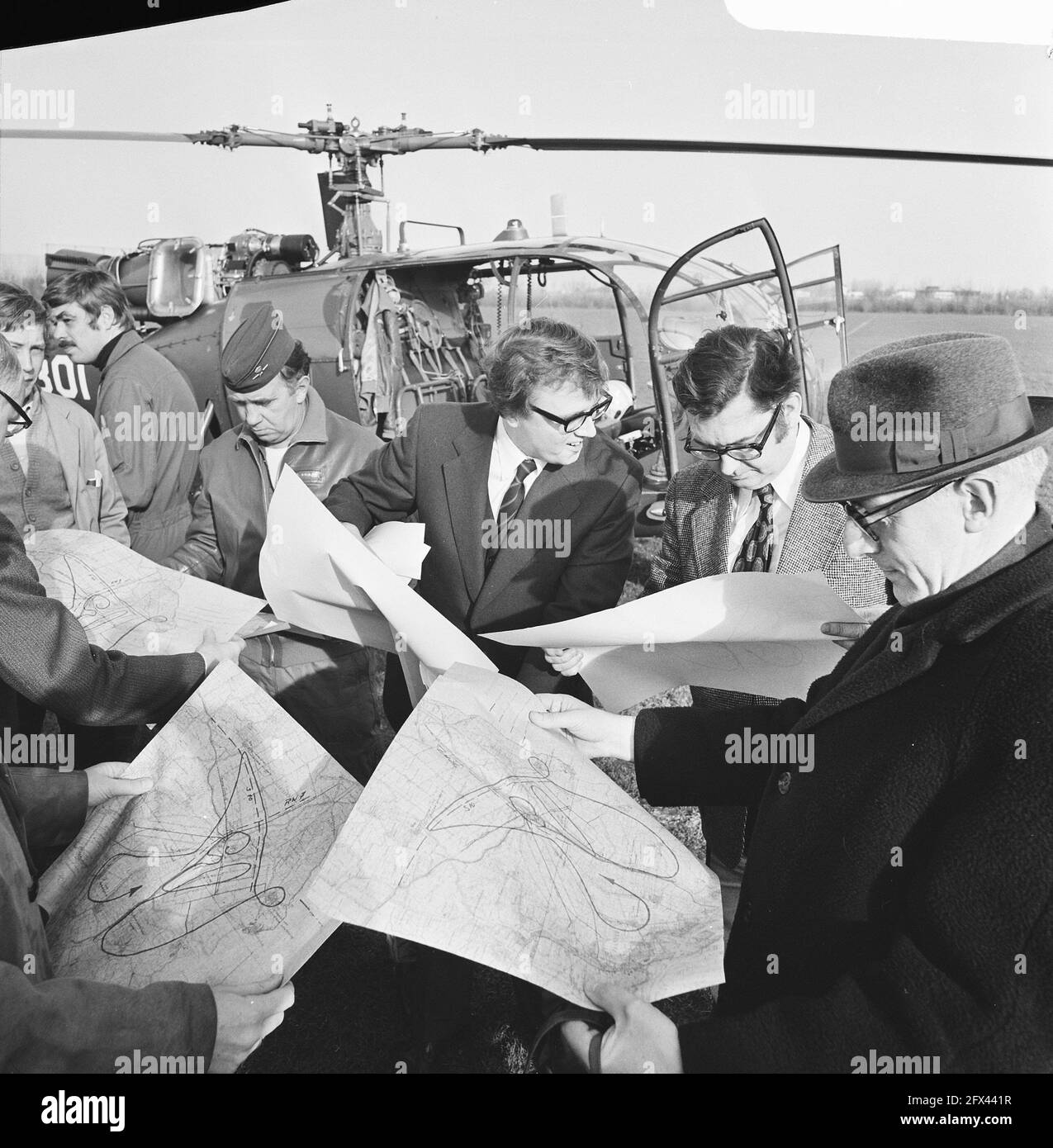 The minister, standing in front of the helicopter, looks at a map ...