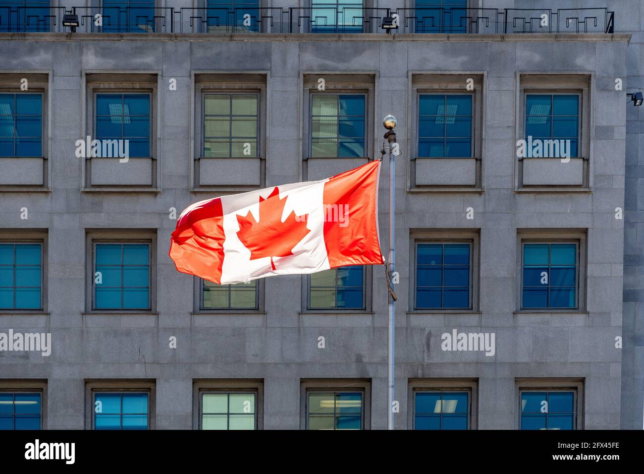 Flag of Canada backlit and against a pattern of windows in the downtown ...