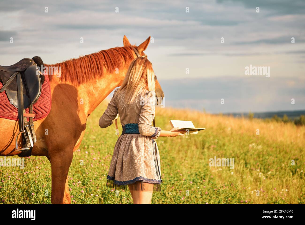 girl with book in the field. woman walking with horse Stock Photo - Alamy