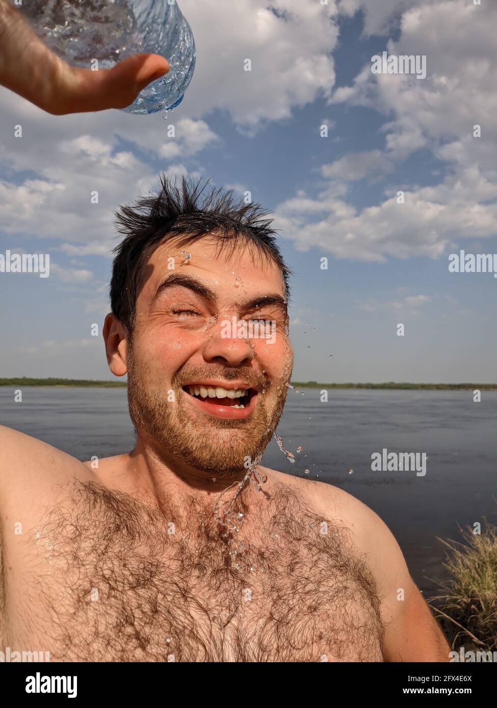 Happy man splashing and pouring fresh water on his head to refresh ...