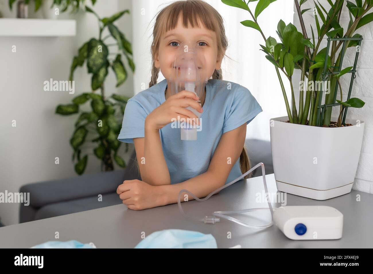 sick little girl makes inhalation over grey background with copy space ...