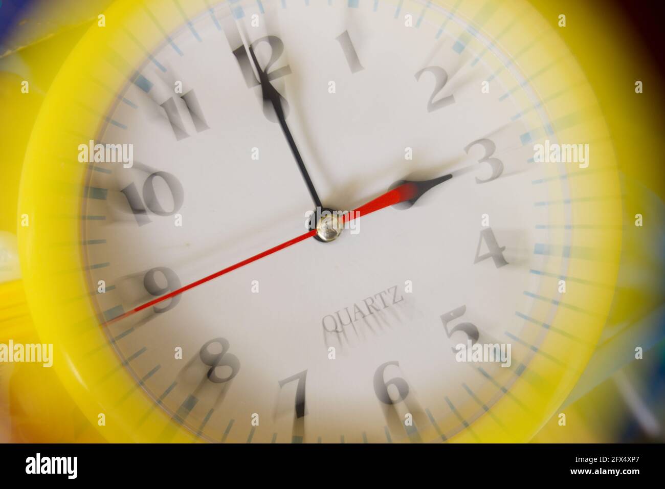 Blurred image of an analog clock that strikes 3 o'clock indicating the ...
