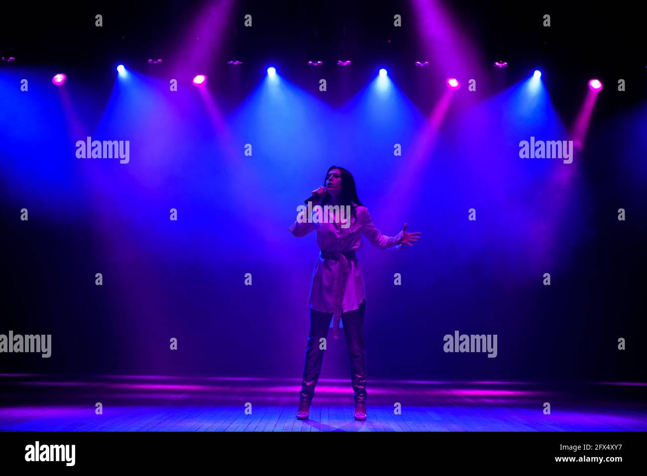 Singer star performing solo set on scene in music hall in neon lights ...